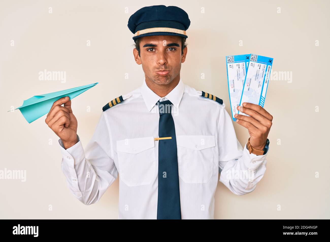 Young hispanic man wearing airplane pilot uniform holding paper ...