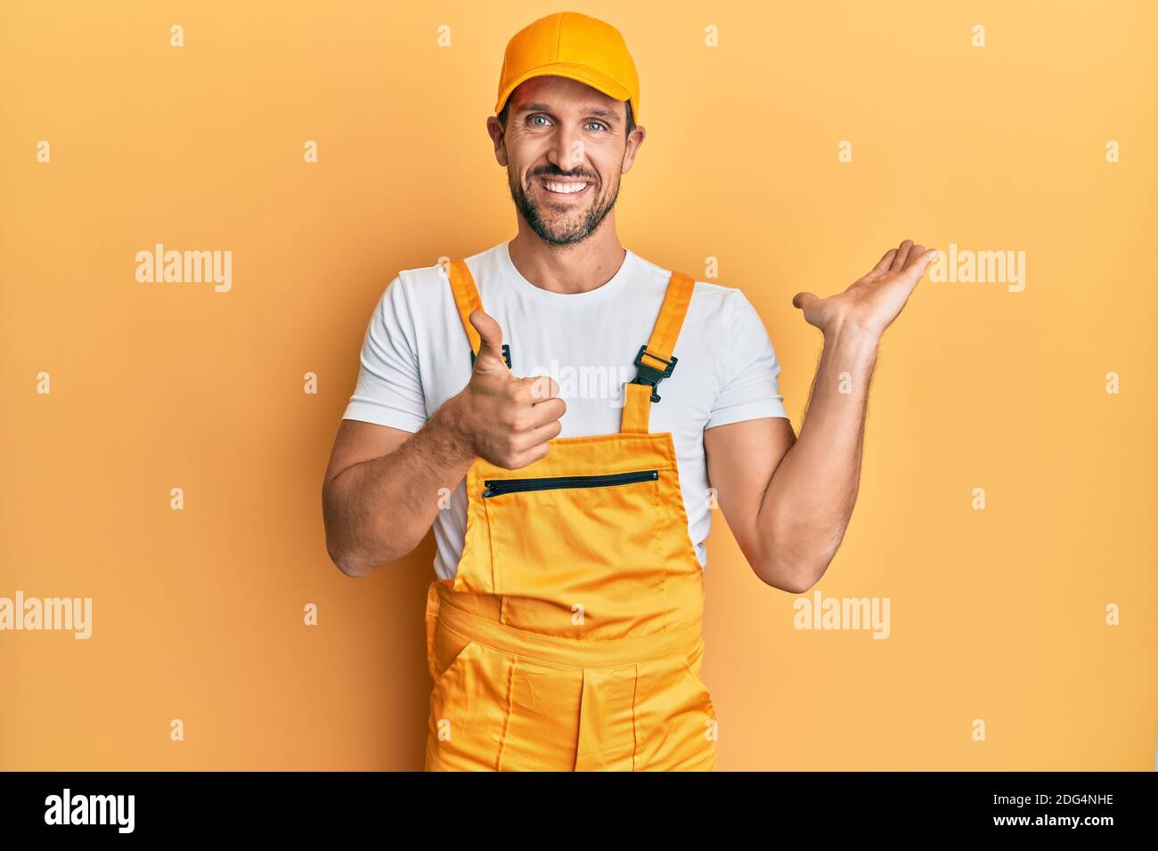 Young handsome man wearing handyman uniform over yellow background ...