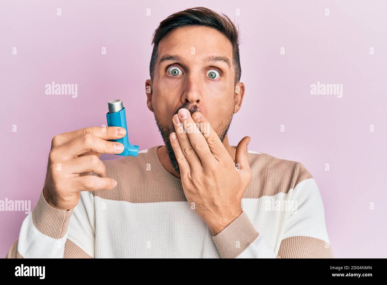 Handsome man with beard holding medical asthma inhaler covering mouth ...