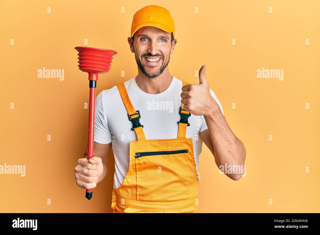 Young handsome man wearing plumber uniform holding toilet plunger ...