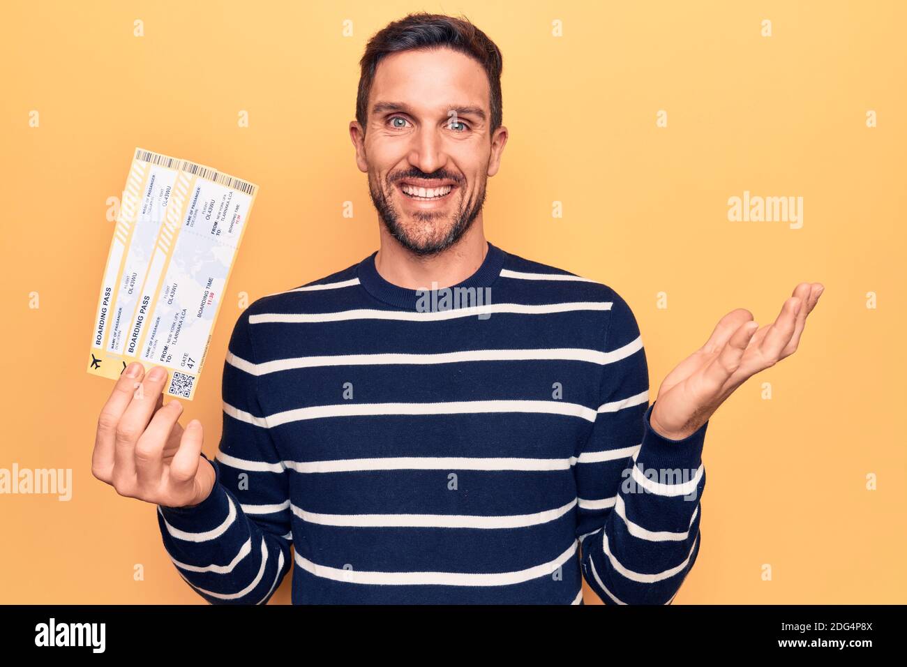 Young handsome tourist man on vacation holding airline boarding pass ...