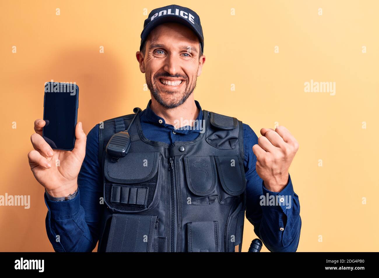 Handsome policeman wearing uniform and bulletprof holding smartphone ...