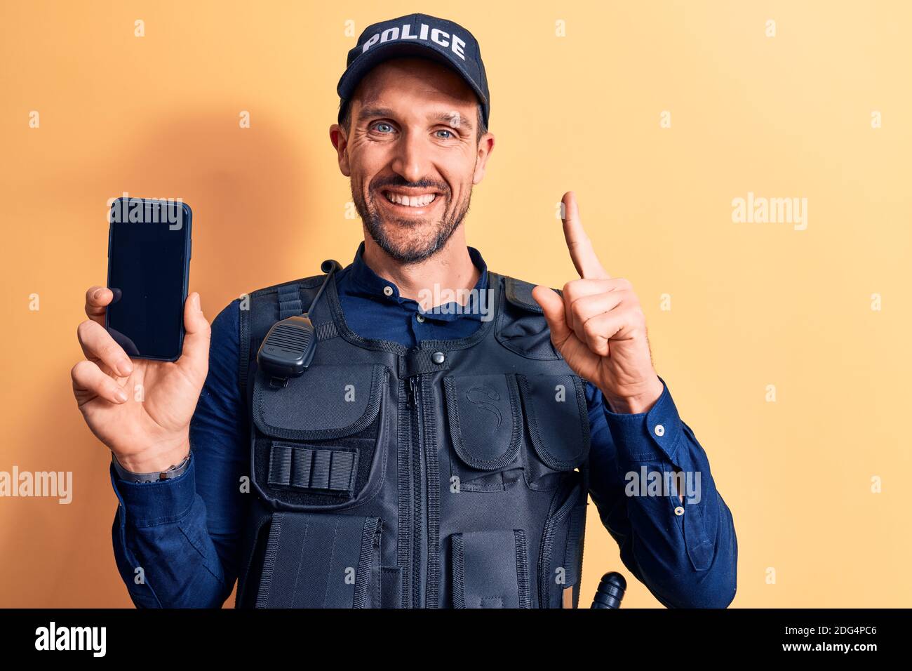 Handsome policeman wearing uniform and bulletprof holding smartphone ...
