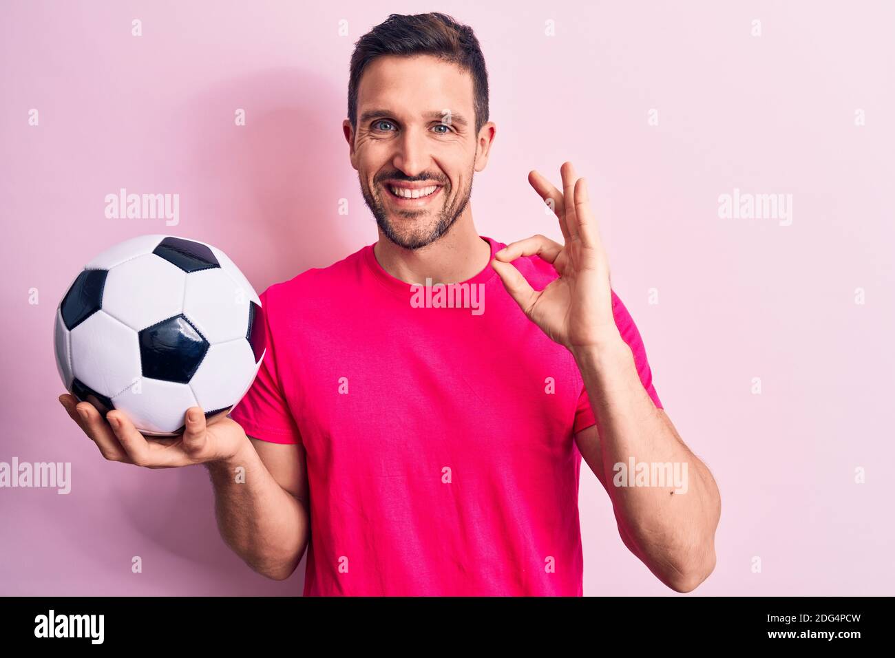 Young handsome player man playing soccer holding football ball over ...