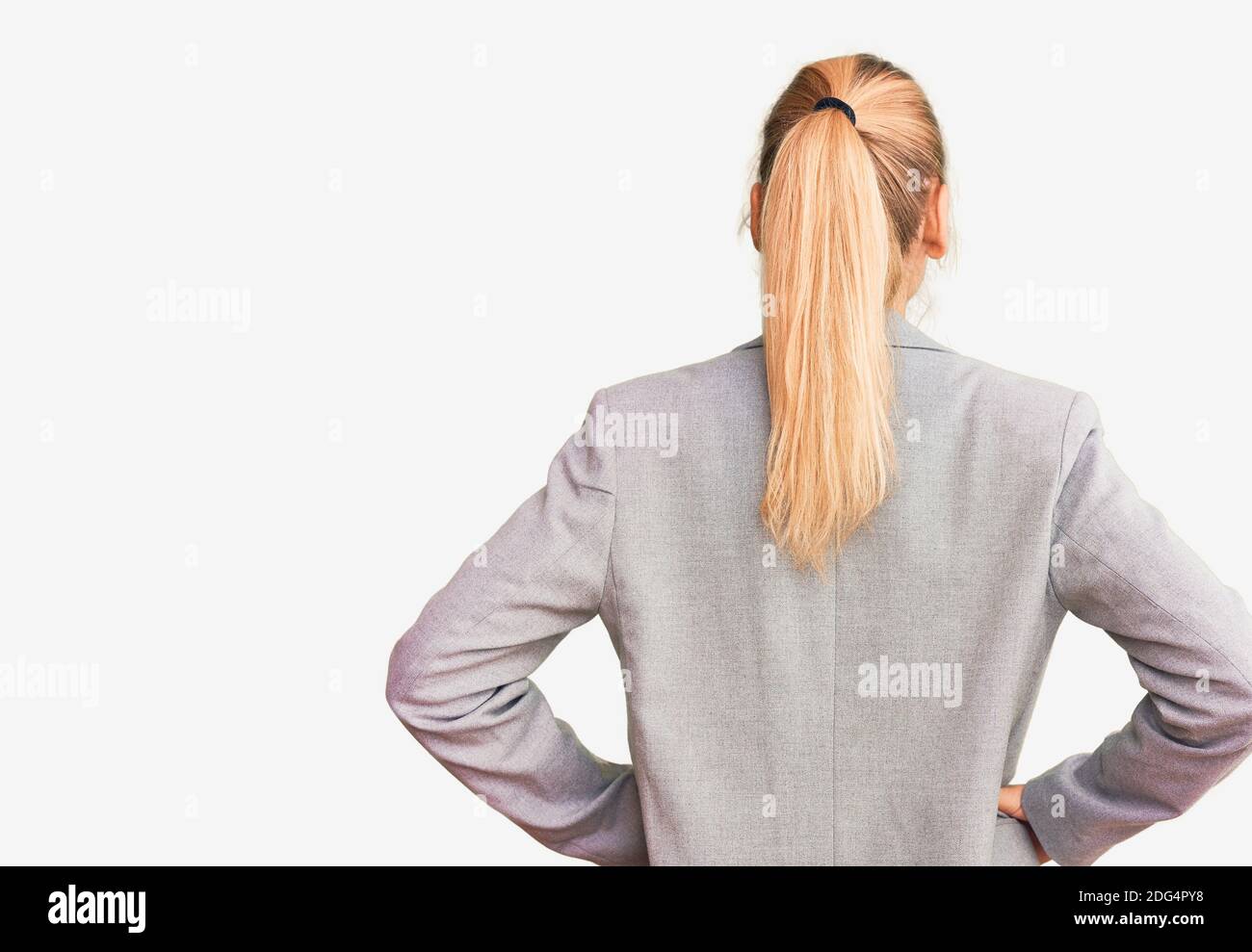 Young beautiful blonde woman wearing elegant jacket standing backwards ...