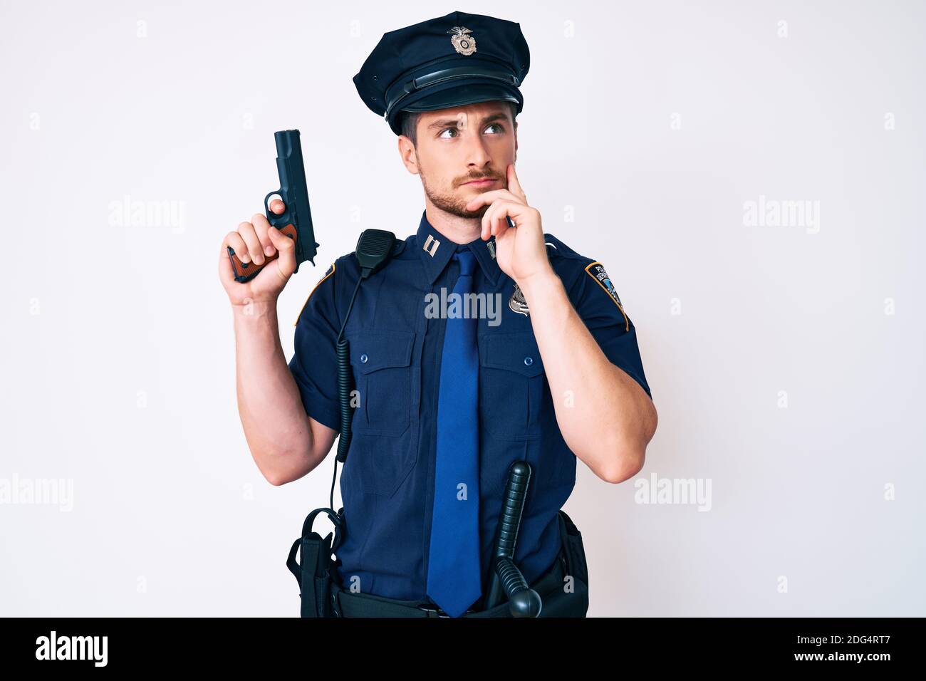 Young caucasian man wearing police uniform holding gun serious face ...