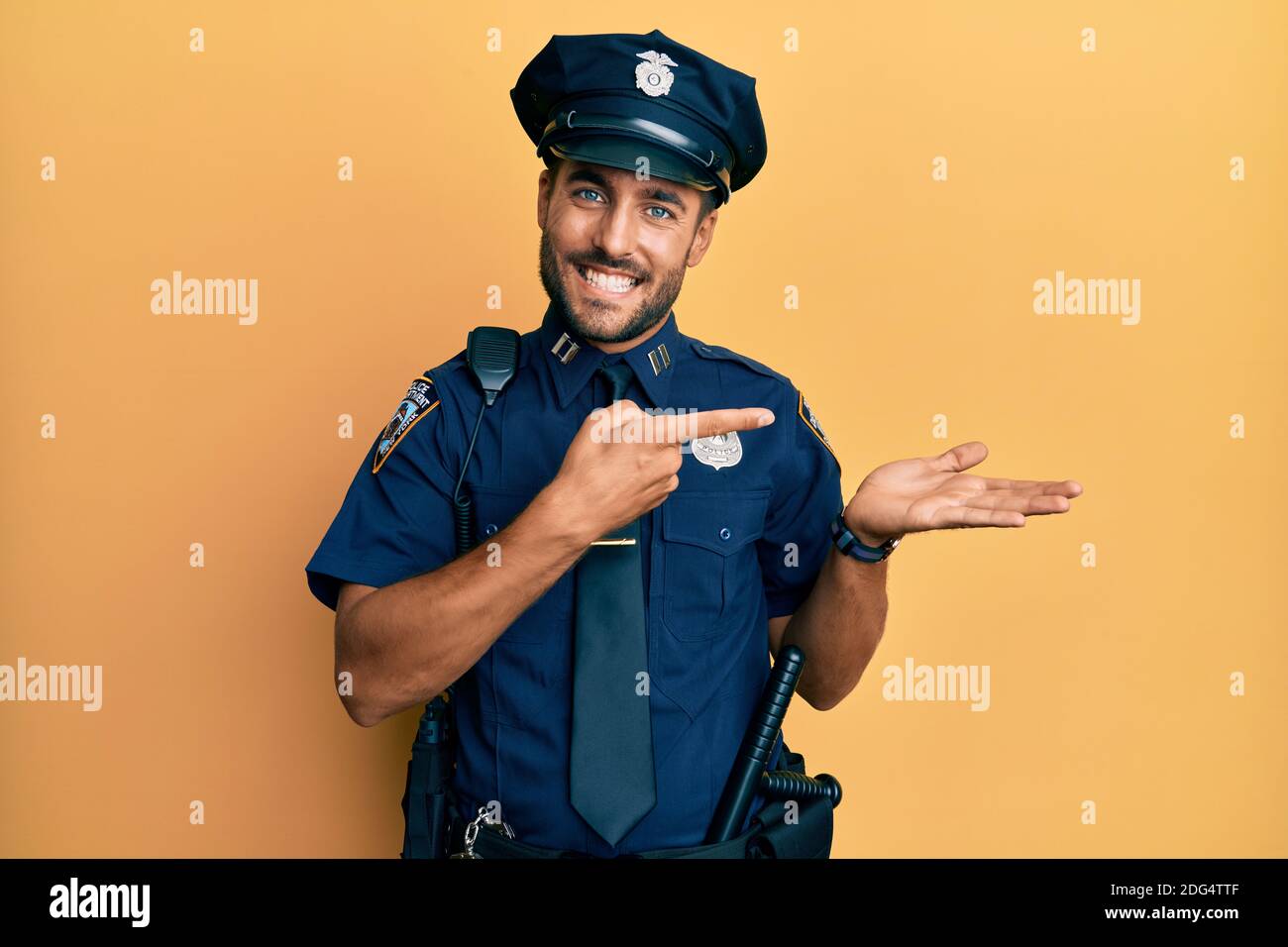 Handsome hispanic man wearing police uniform amazed and smiling to the ...