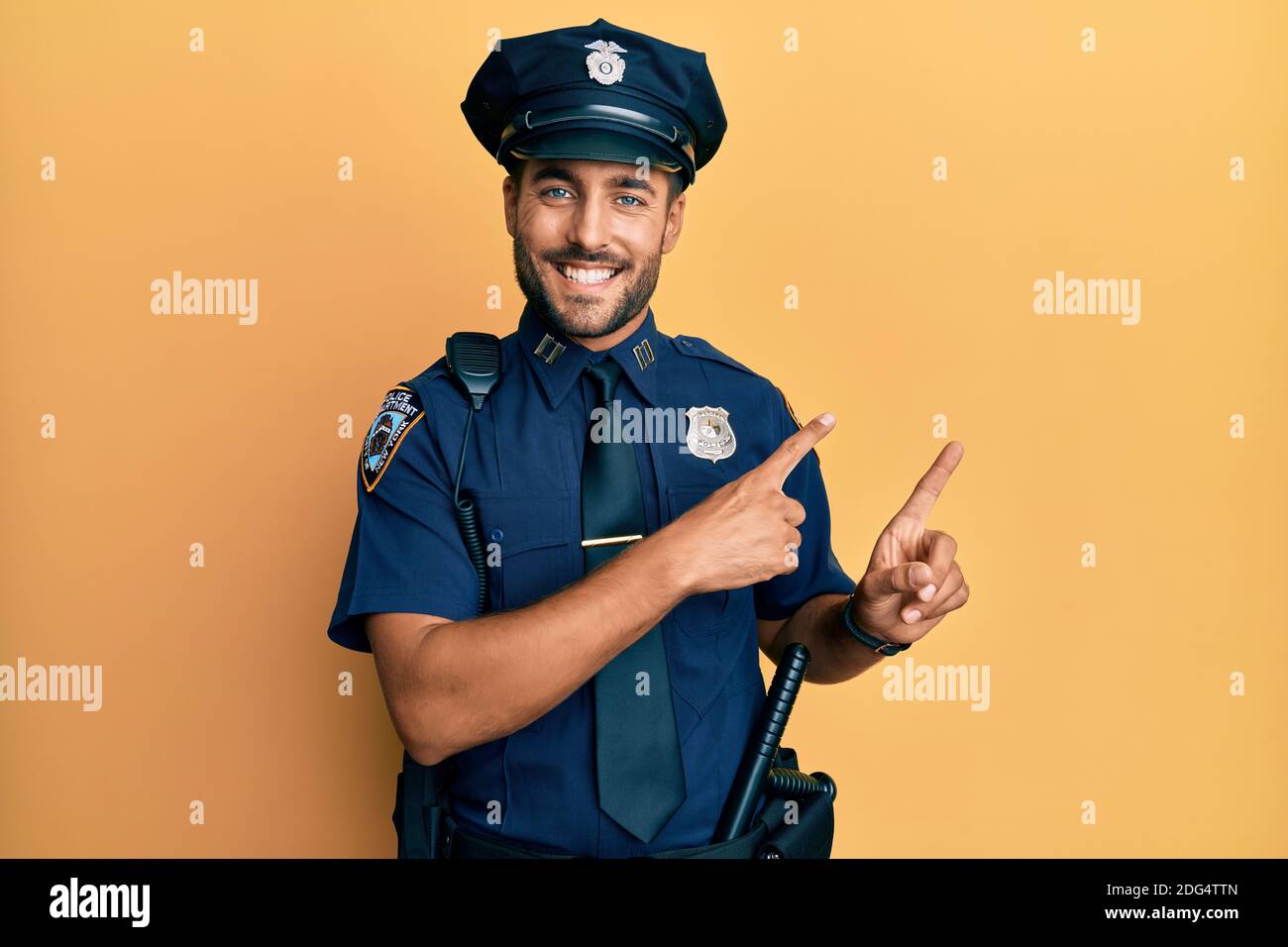 Handsome hispanic man wearing police uniform smiling and looking at the ...