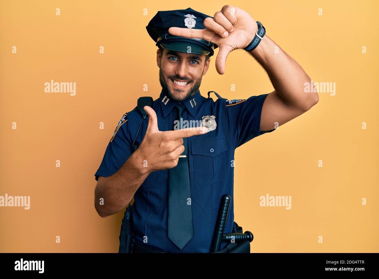 Handsome hispanic man wearing police uniform smiling making frame with ...