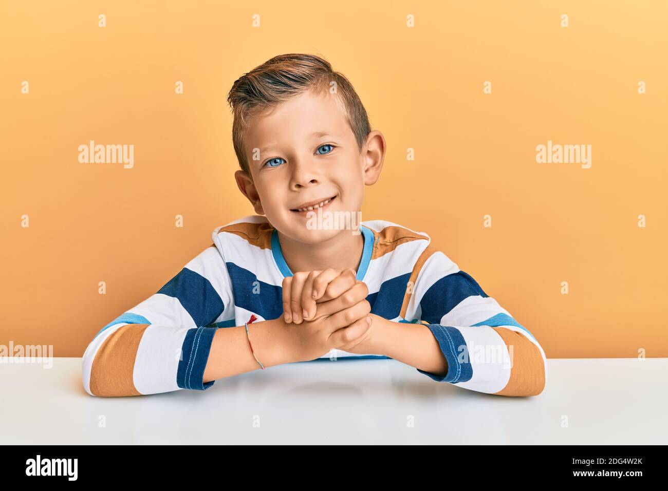 Adorable caucasian kid wearing casual clothes sitting on the table with ...