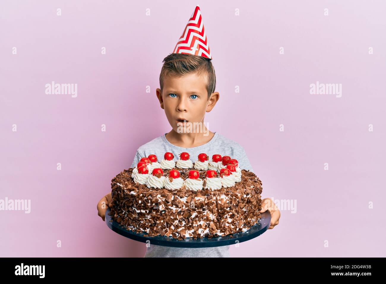 Adorable caucasian kid celebrating birthday with cake in shock face ...