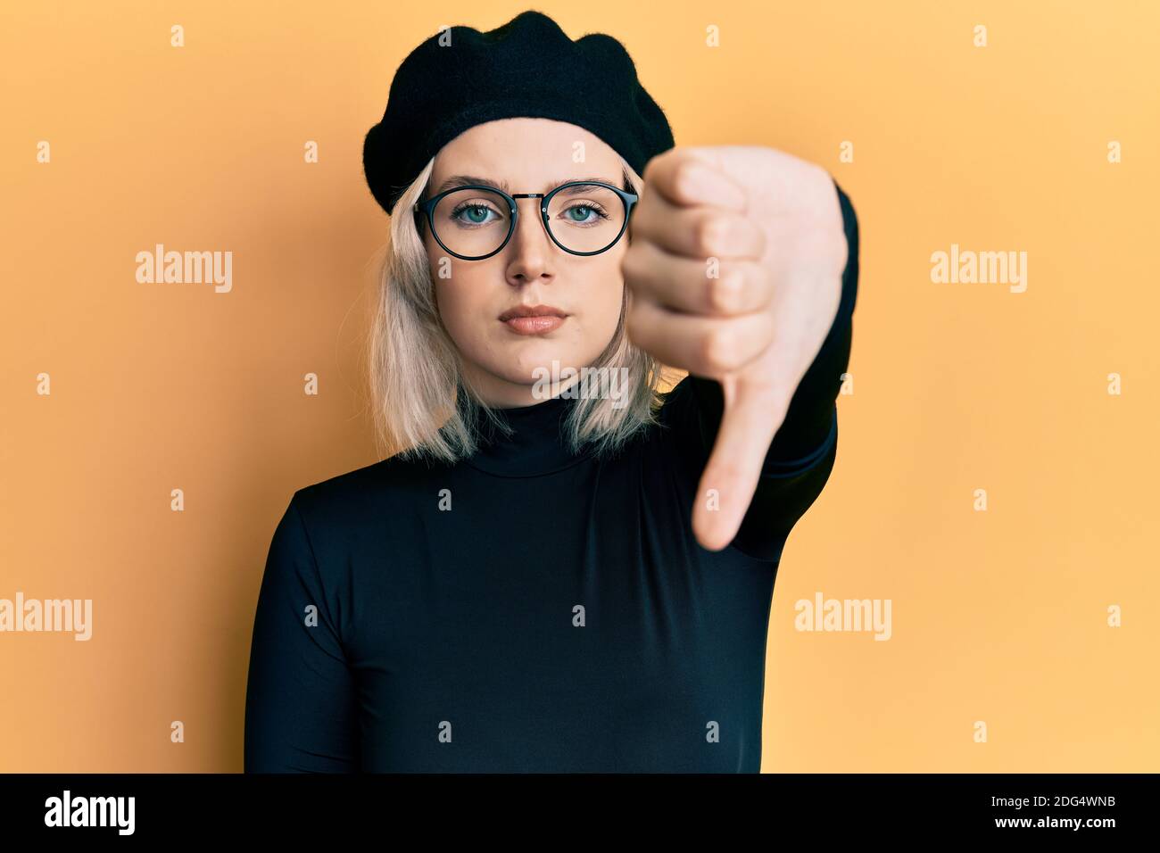 Young blonde girl wearing french look with beret looking unhappy and ...