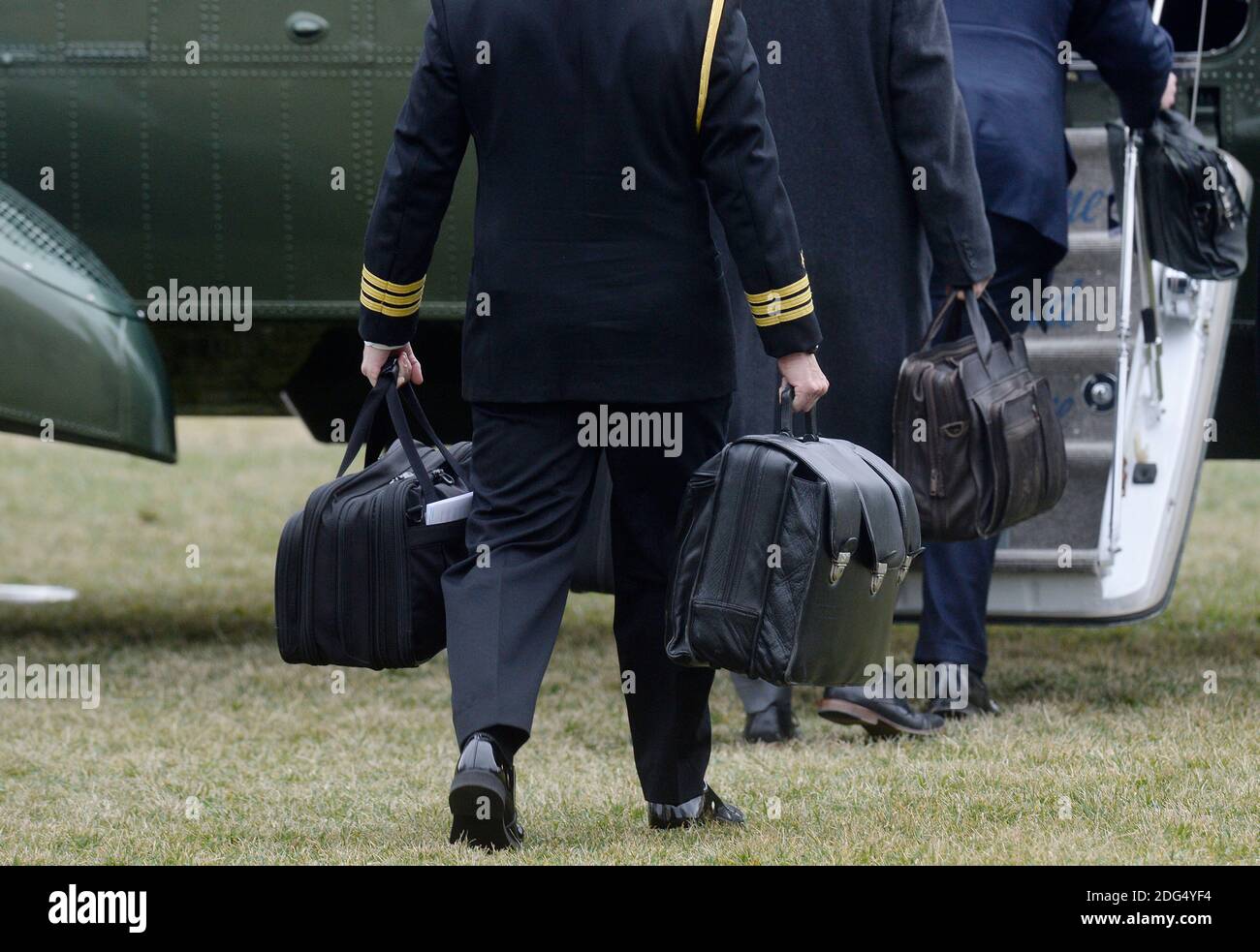 A military aide carries the nuclear football as he prepare to travel ...
