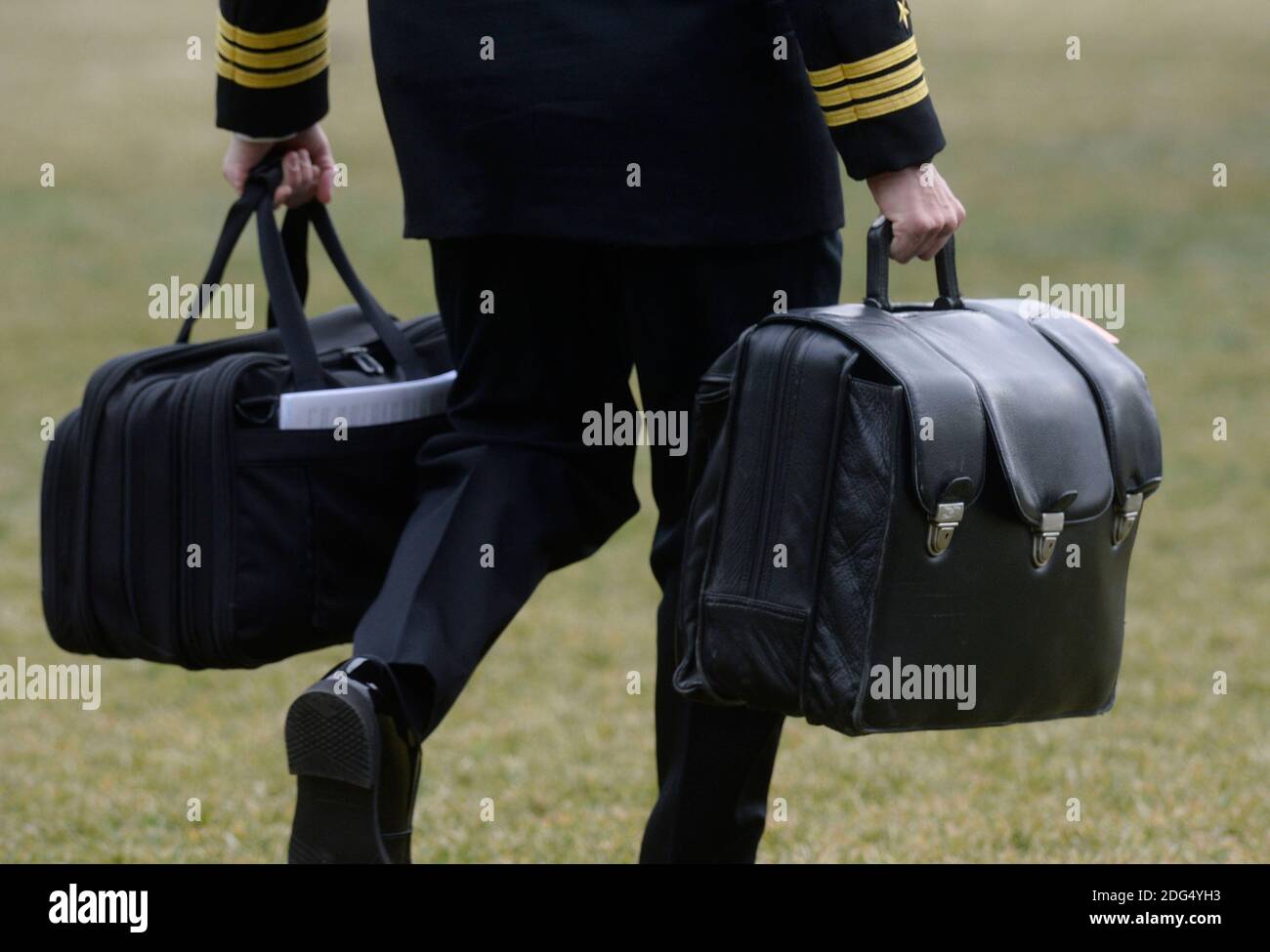 A military aide carries the nuclear football as he prepare to travel ...