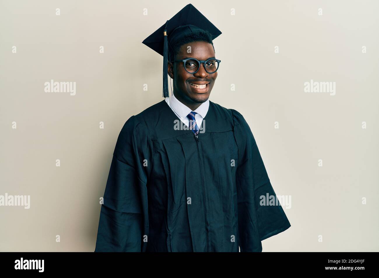 Handsome black man wearing graduation cap and ceremony robe with a ...