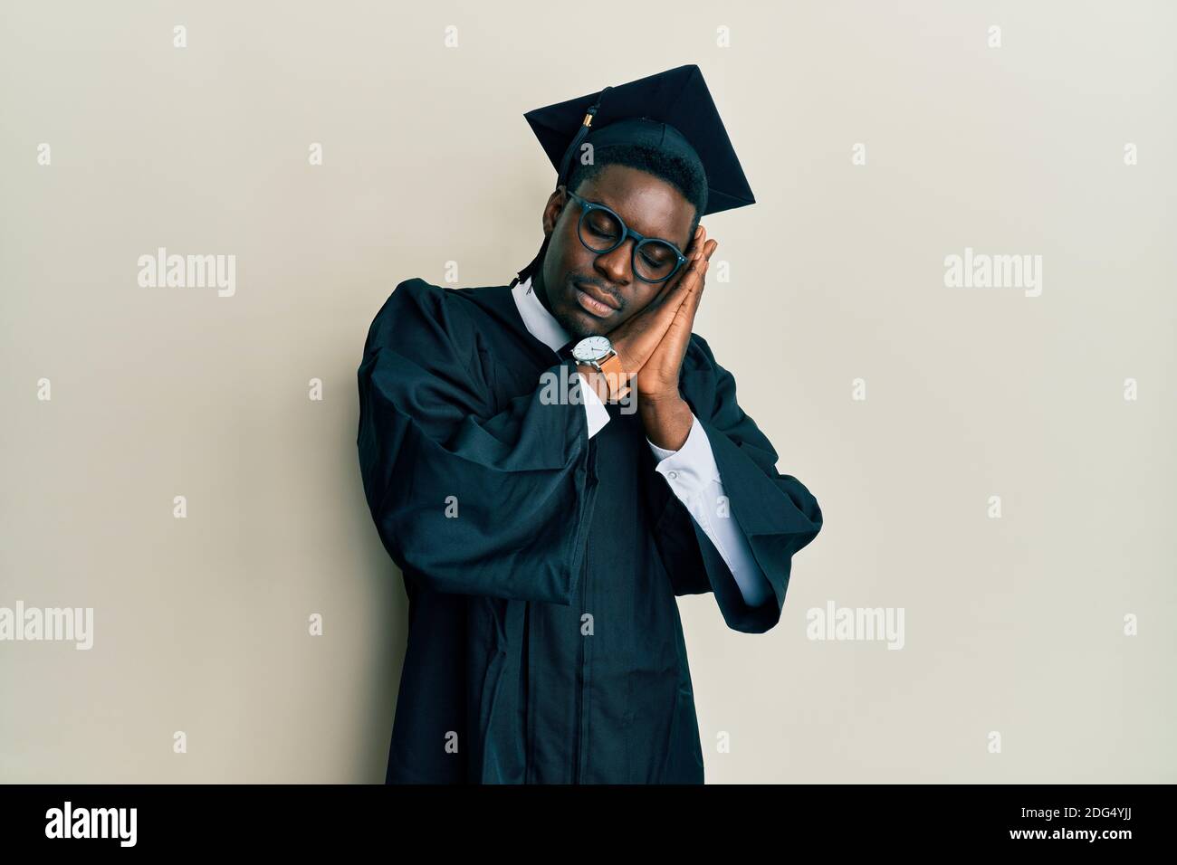 Handsome black man wearing graduation cap and ceremony robe sleeping ...