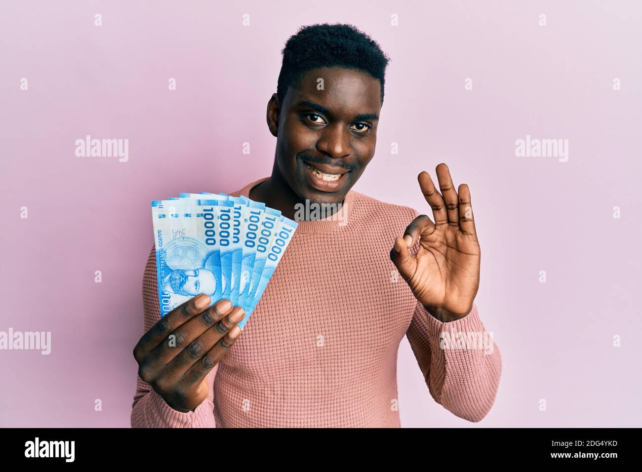 Handsome black man holding 10000 chilean pesos doing ok sign with ...