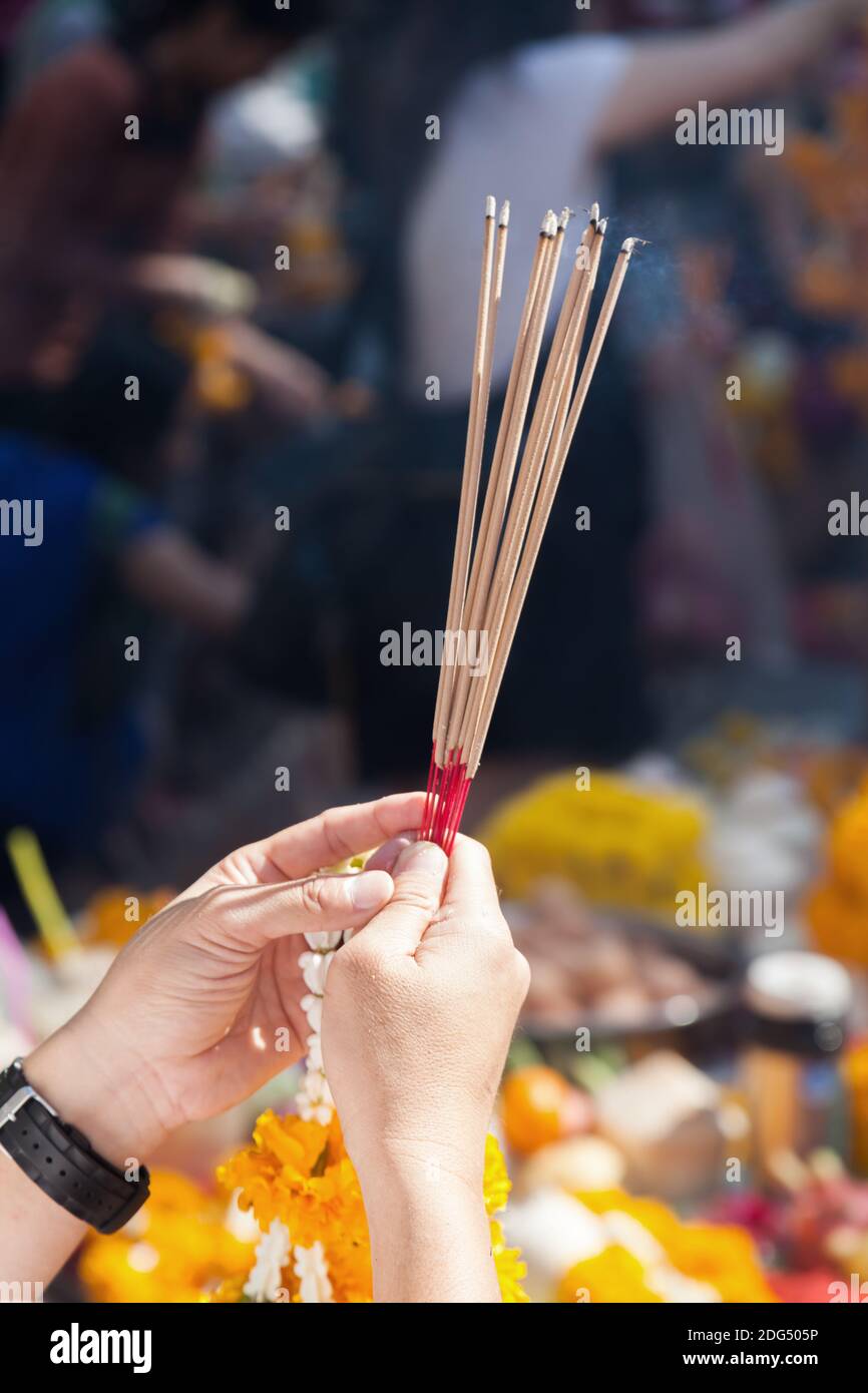Hands of a woman holding incense sticks at the Erawan Shrine in Bangkok ...