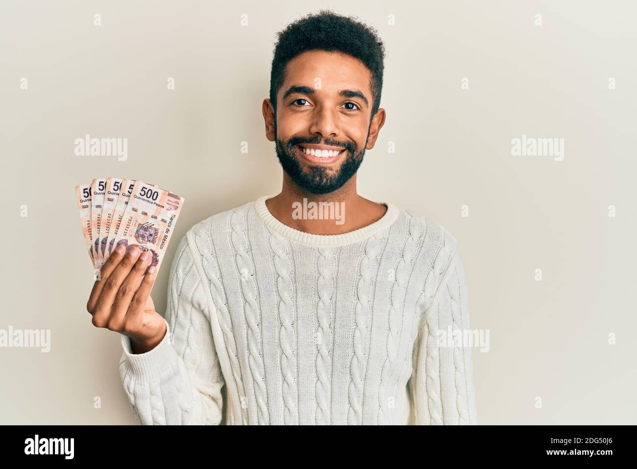 Handsome hispanic man with beard holding 500 mexican pesos banknotes ...