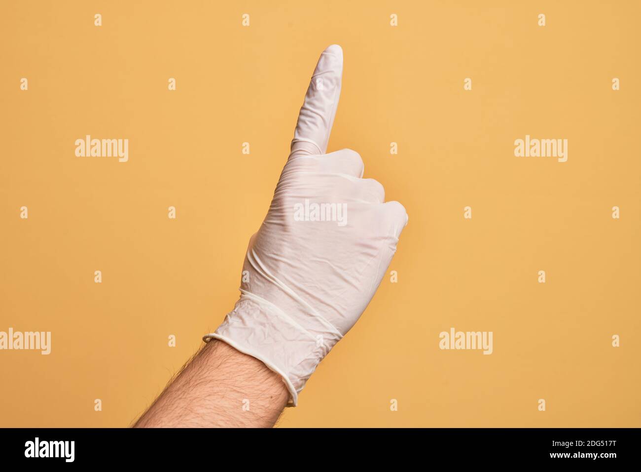 Hand of caucasian young man with medical glove over isolated yellow ...