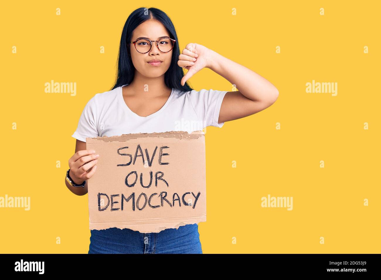 Young beautiful asian girl holding save our democracy protest banner ...