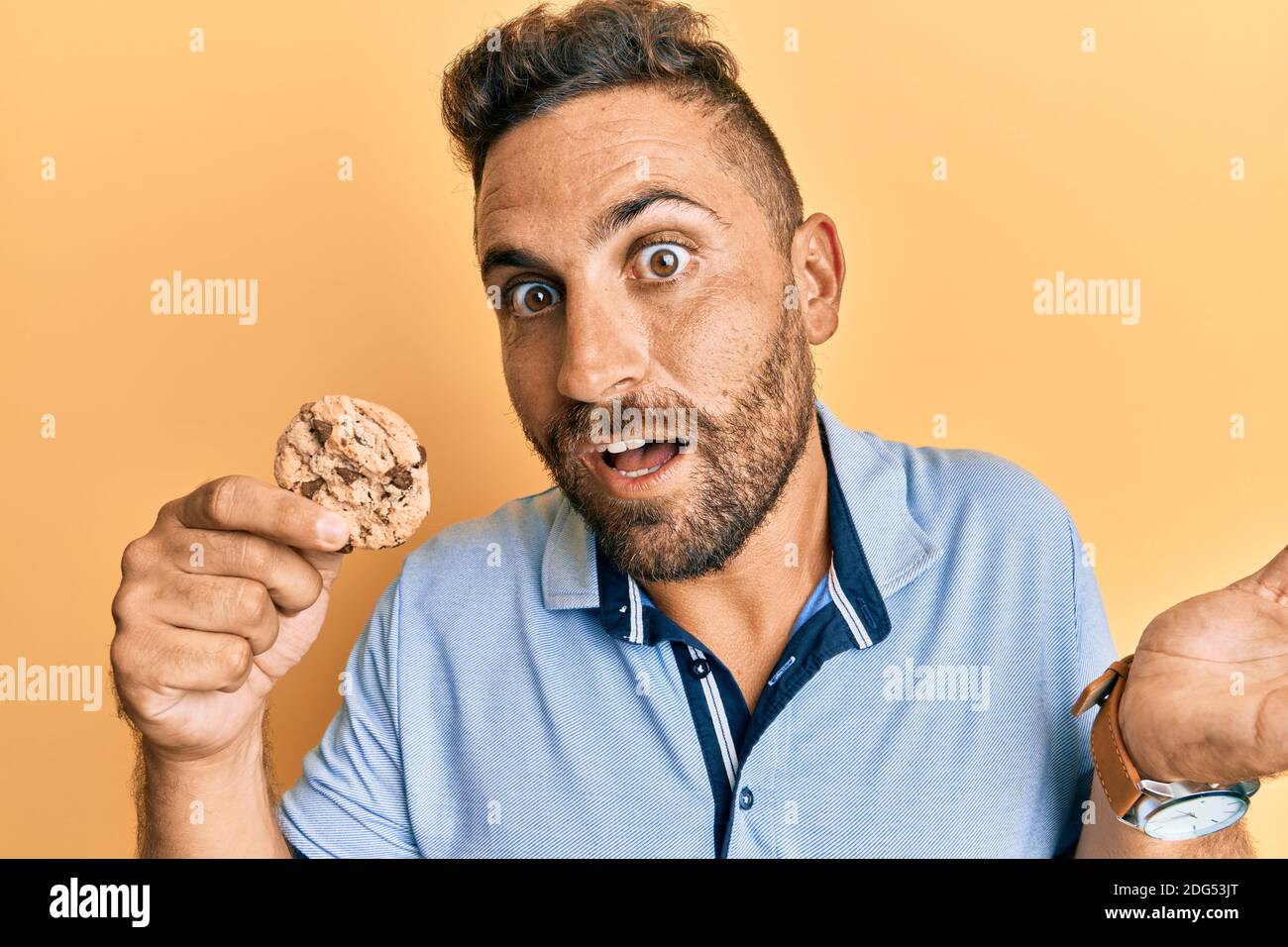 Handsome man with beard holding cookie celebrating achievement with ...