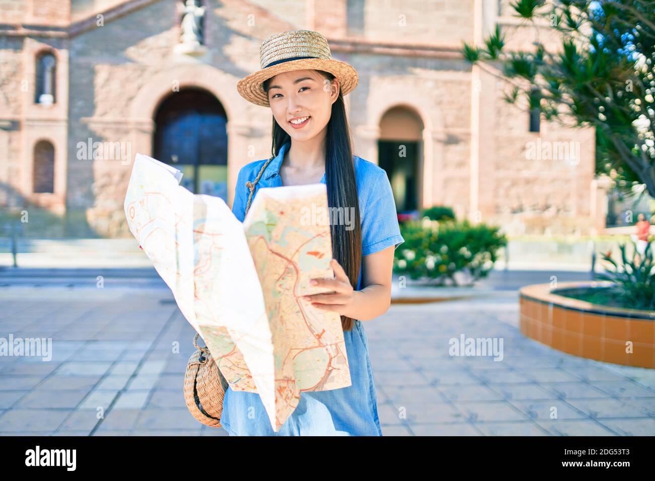 Young chinese tourist woman smiling happy holding city map at the park ...