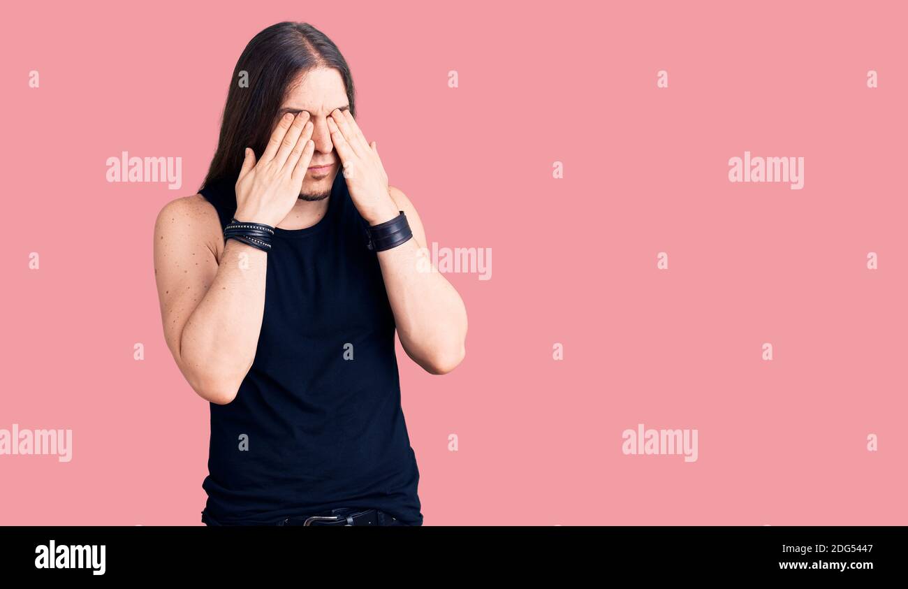 Young adult man with long hair wearing goth style with black clothes ...