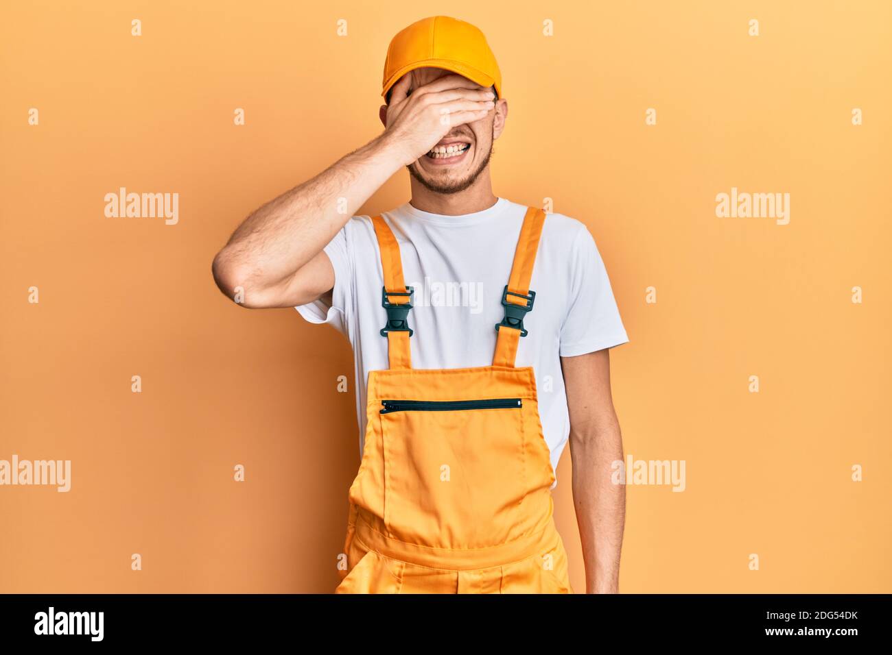Hispanic young man wearing handyman uniform smiling and laughing with ...