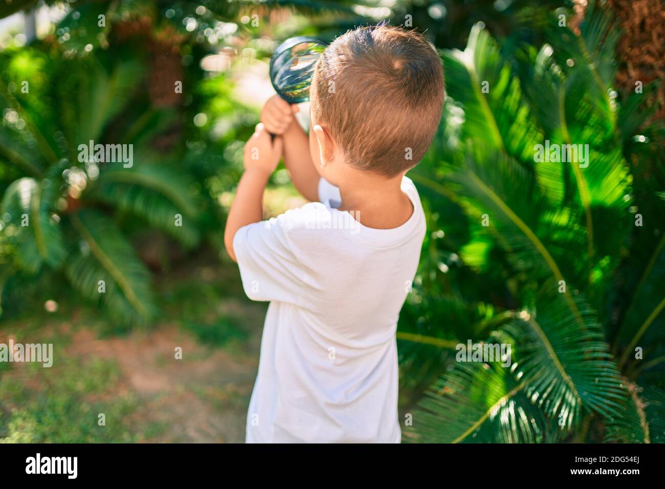 Adorable hispanic boy using magnifying glass playing at the park Stock ...