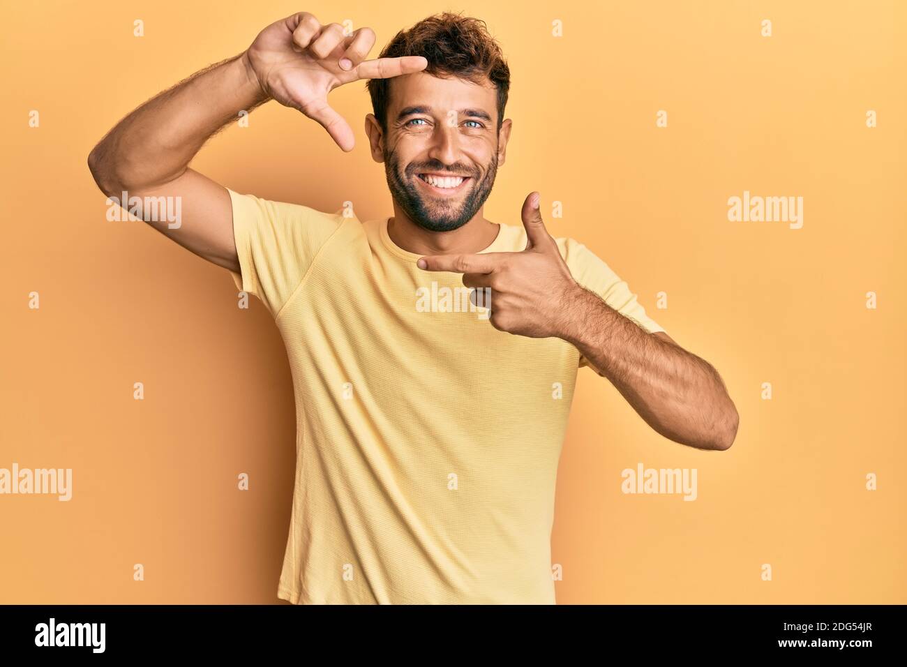 Handsome man with beard wearing casual yellow tshirt over yellow ...