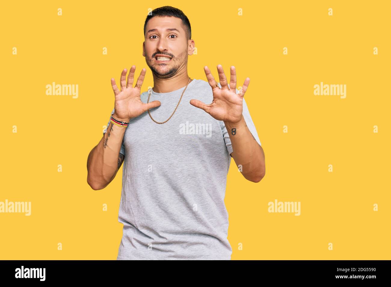 Handsome man with tattoos wearing 90s style afraid and terrified with ...