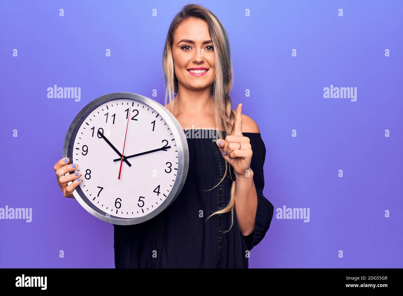 Young beautiful blonde woman doing countdown using big clock over ...