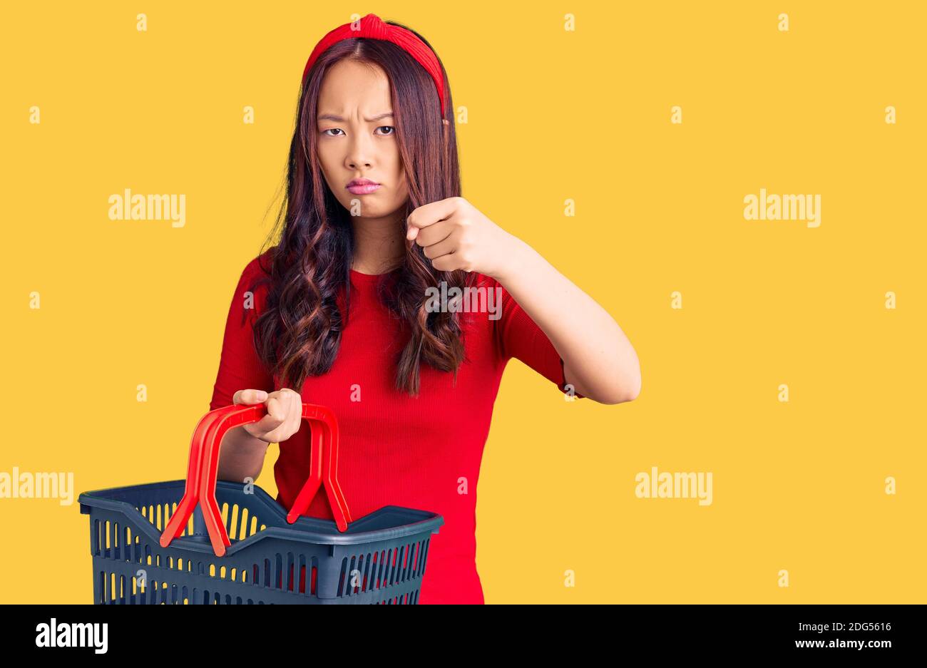 Young beautiful chinese girl holding supermarket shopping basket ...