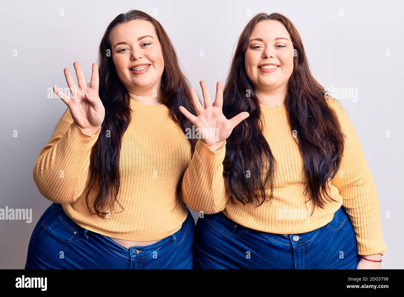 Young plus size twins wearing casual clothes showing and pointing up ...