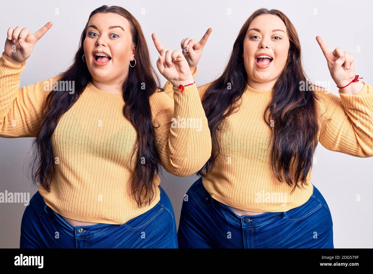 Young plus size twins wearing casual clothes smiling amazed and ...