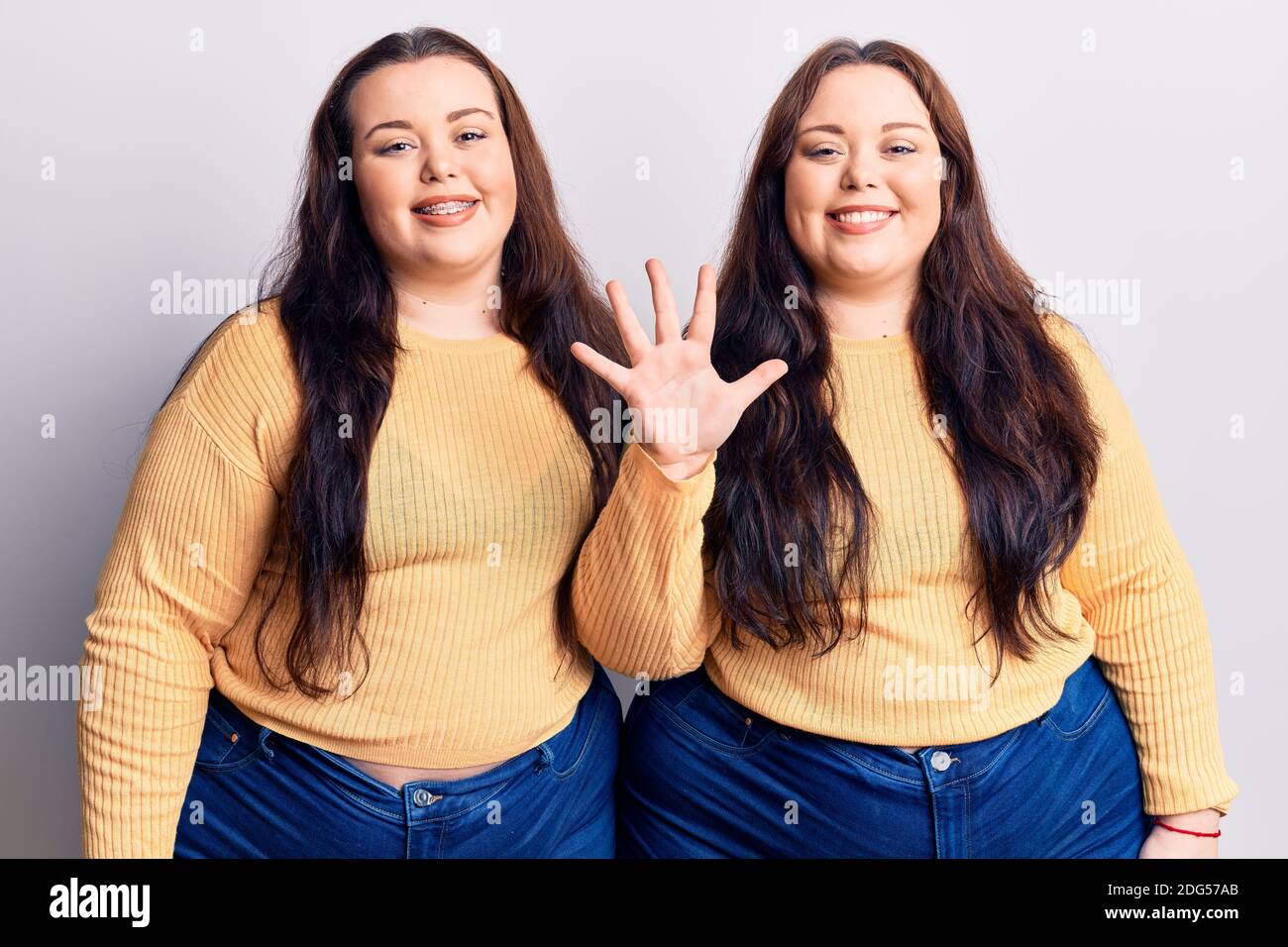 Young plus size twins wearing casual clothes showing and pointing up ...