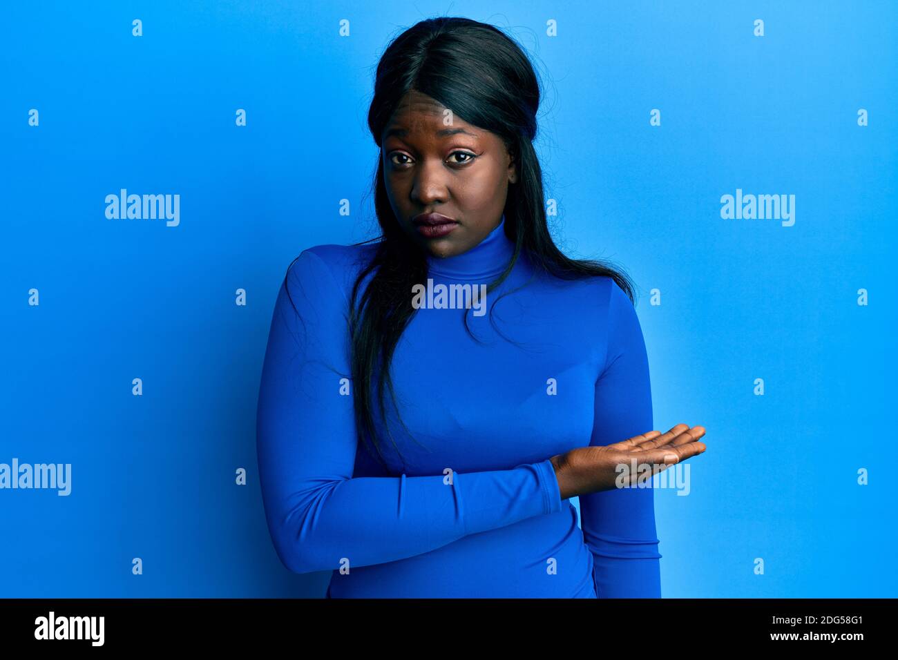 African young woman presenting with open palm to the side skeptic and ...
