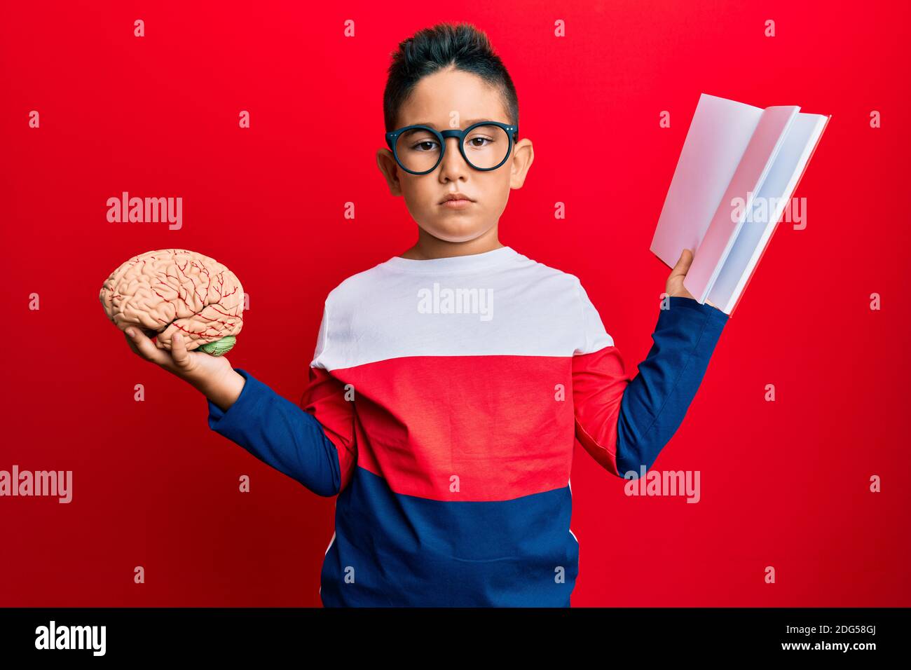 Little boy hispanic kid holding brain studying for school relaxed with ...