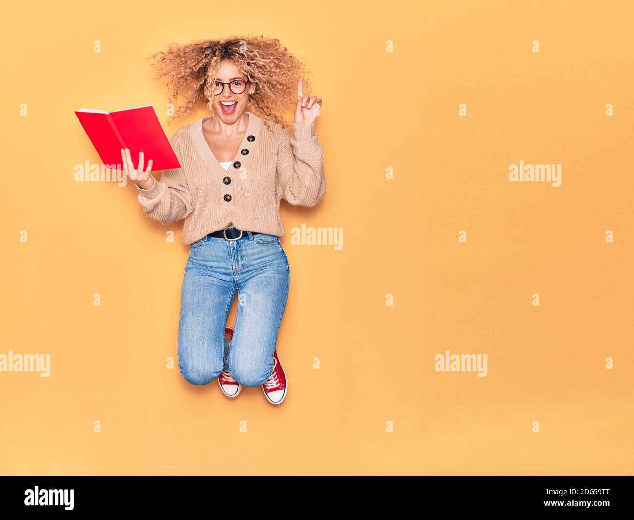 Young beautiful curly student girl wearing glasses smiling happy ...