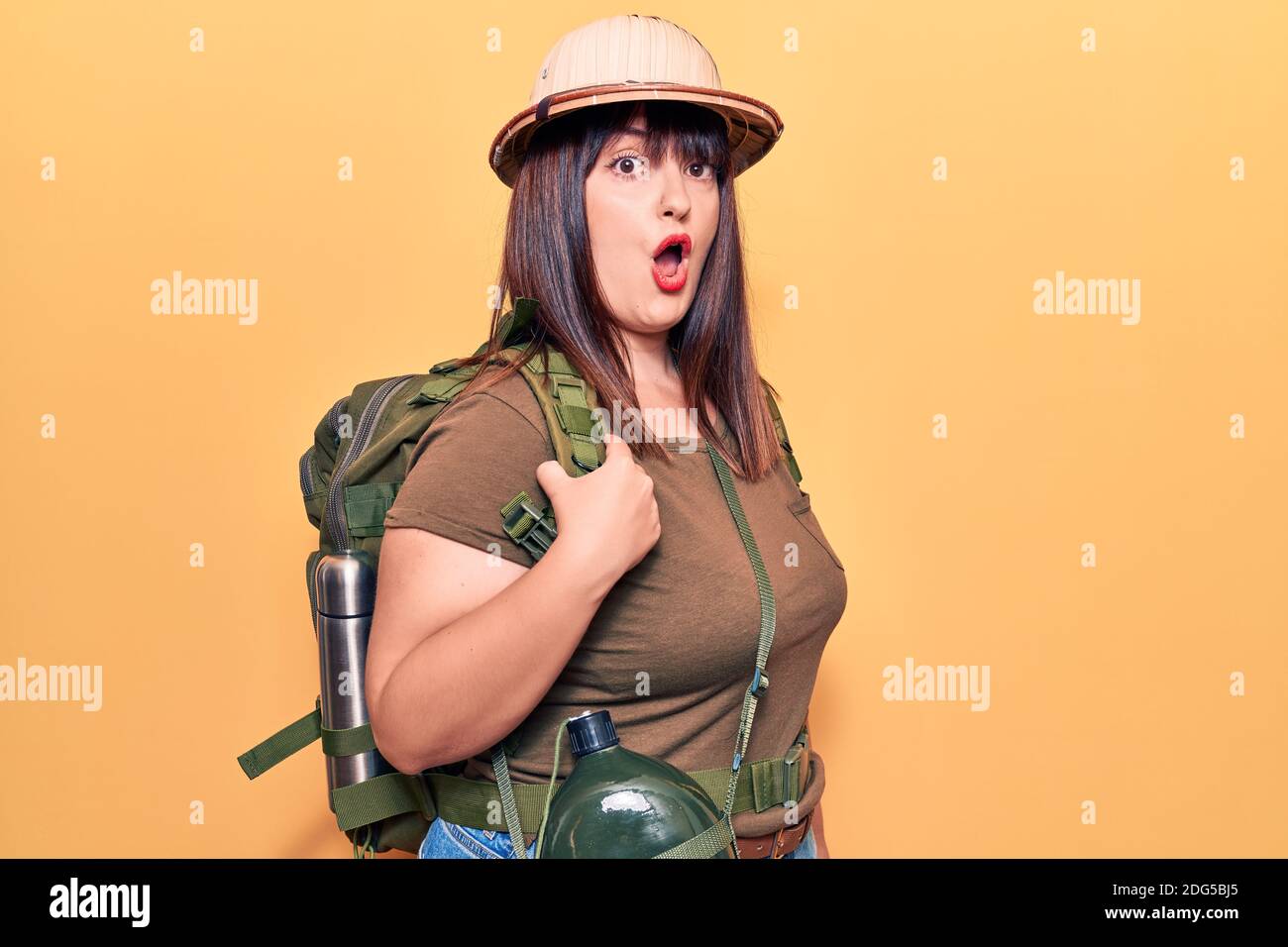 Young plus size woman wearing explorer hat and backpack scared and ...