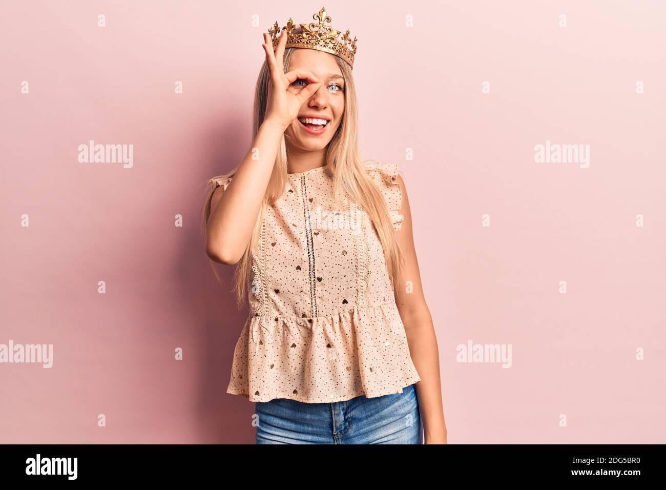Young blonde woman wearing princess crown smiling happy doing ok sign ...