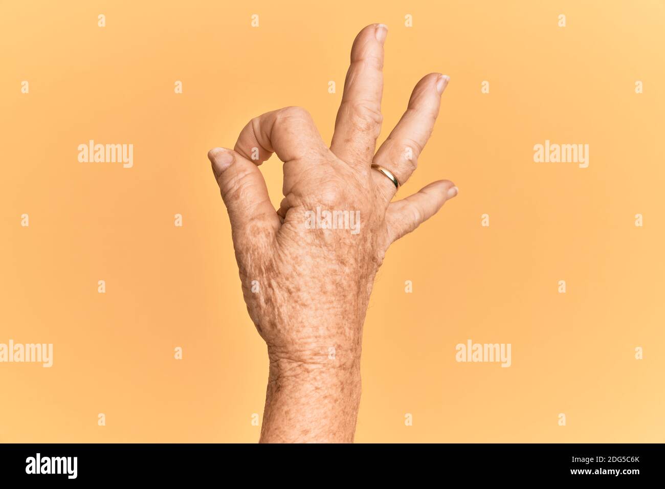 Senior caucasian hand over yellow isolated background gesturing ...
