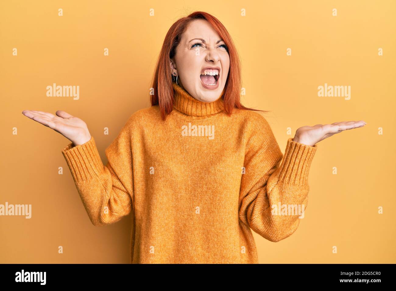 Beautiful redhead woman presenting with open palm angry and mad ...