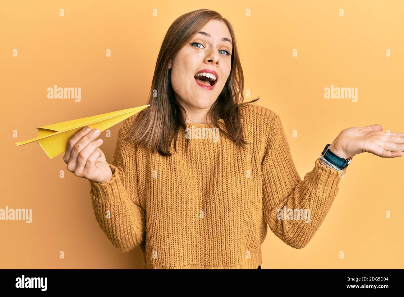 Beautiful caucasian woman holding paper airplane celebrating ...