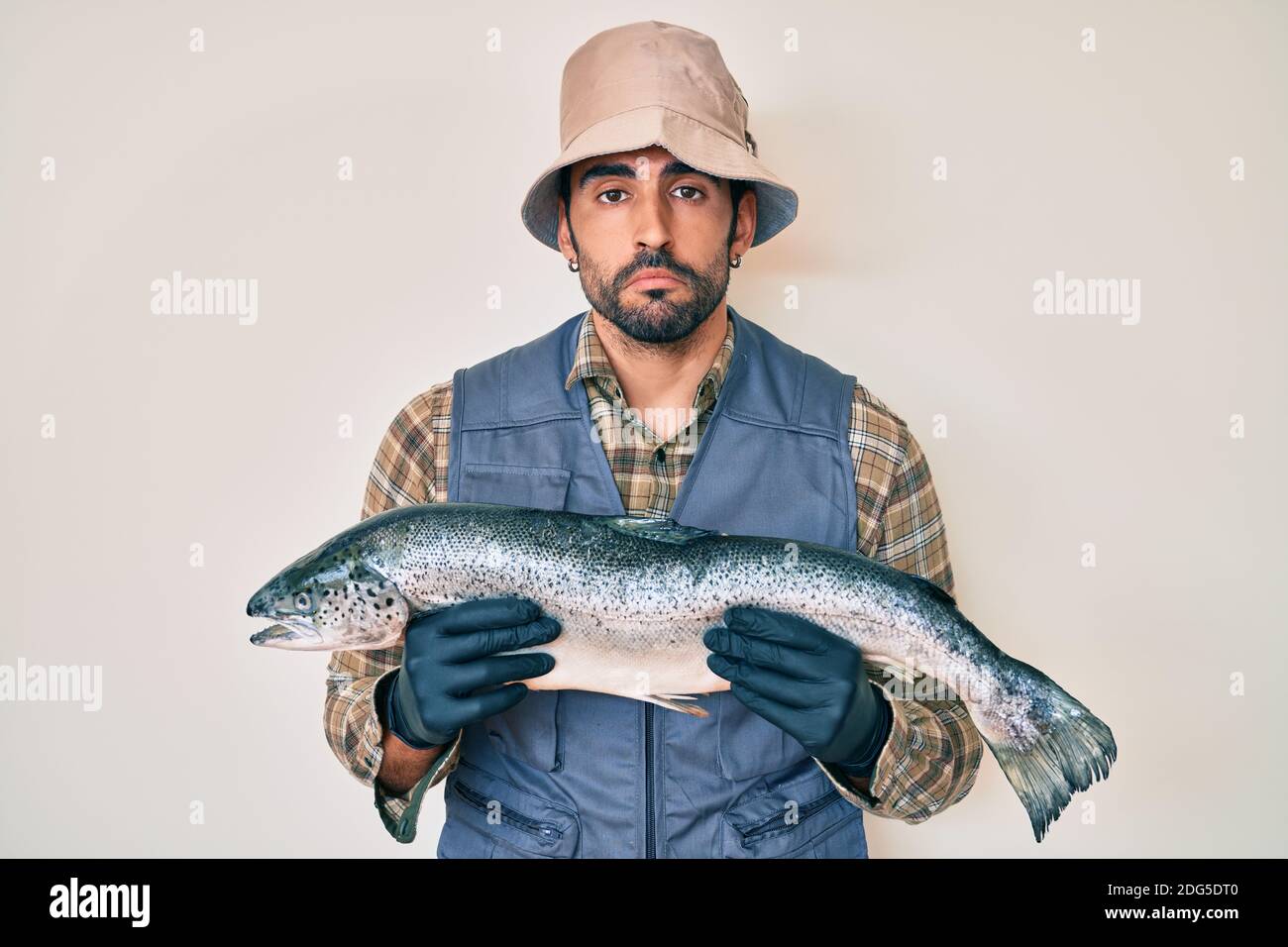 Handsome hispanic man with beard showing raw salmon depressed and worry ...