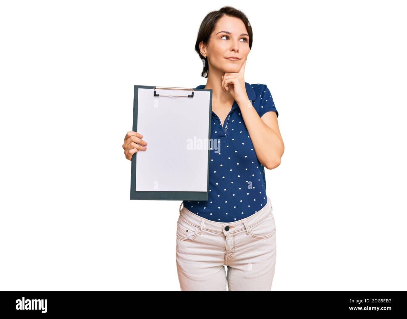 Young brunette woman with short hair holding clipboard with blank space ...