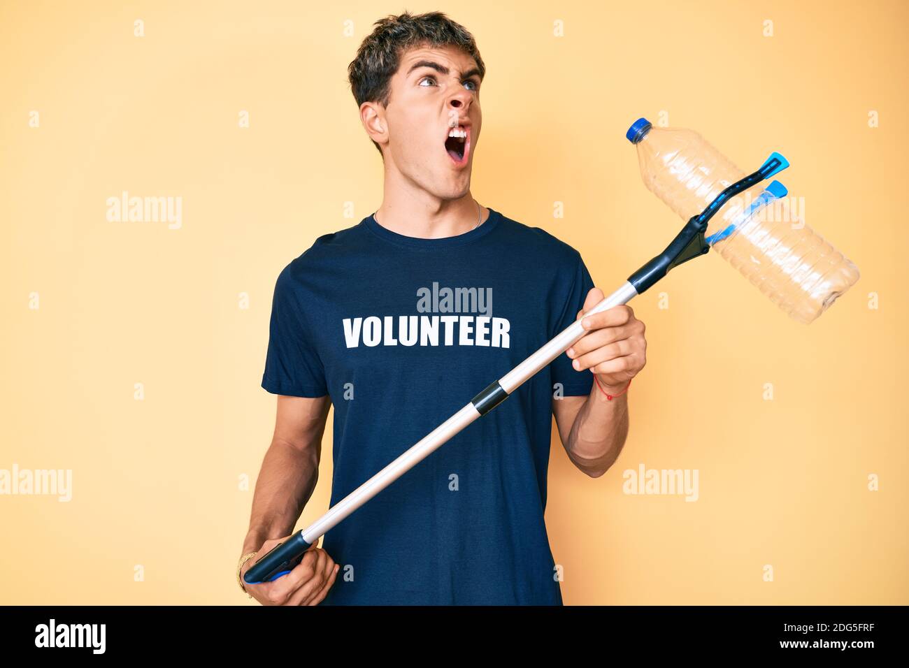 Young handsome man recycling plastic bottle holding litter pick up tool ...