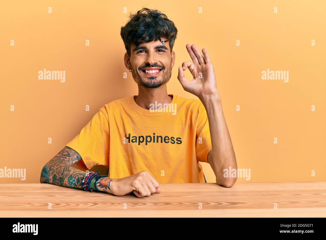 Young hispanic man wearing tshirt with happiness word message sitting ...