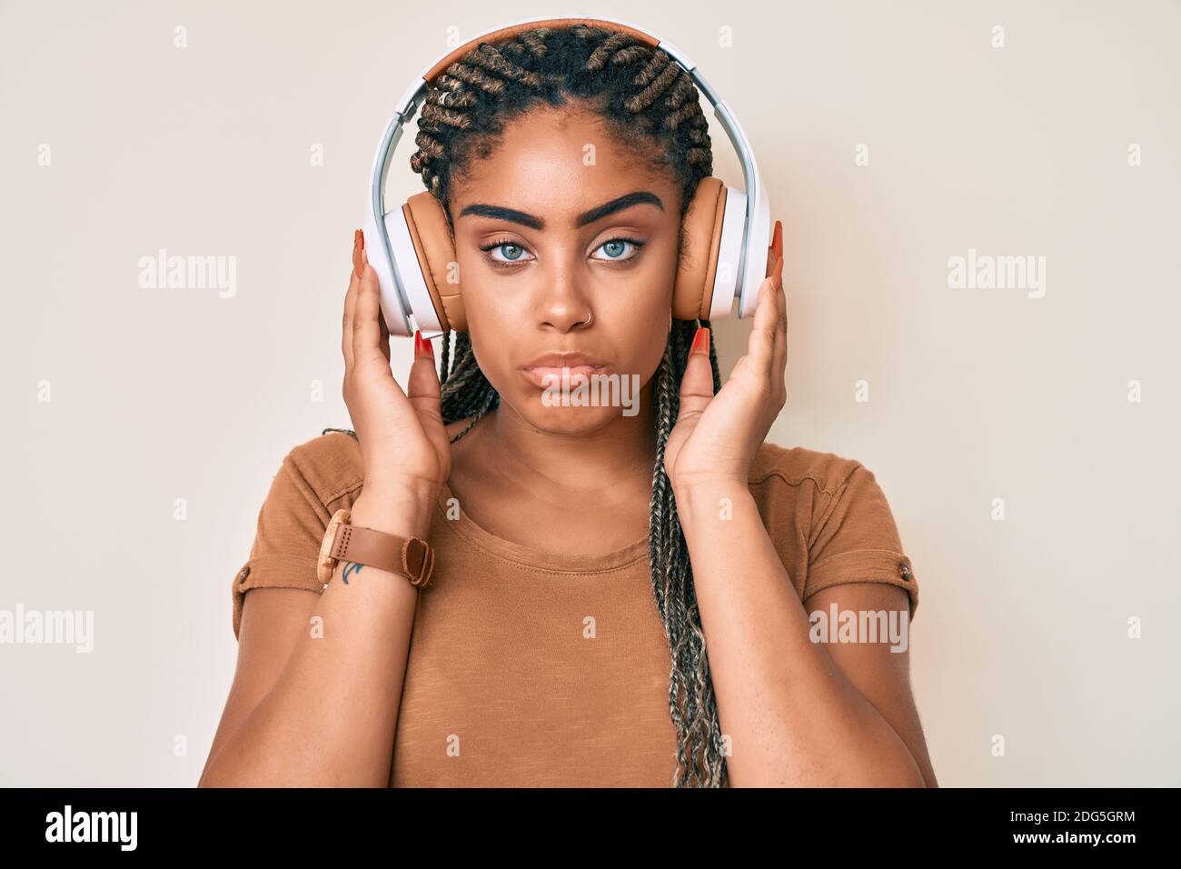 Young african american woman with braids listening to music using ...